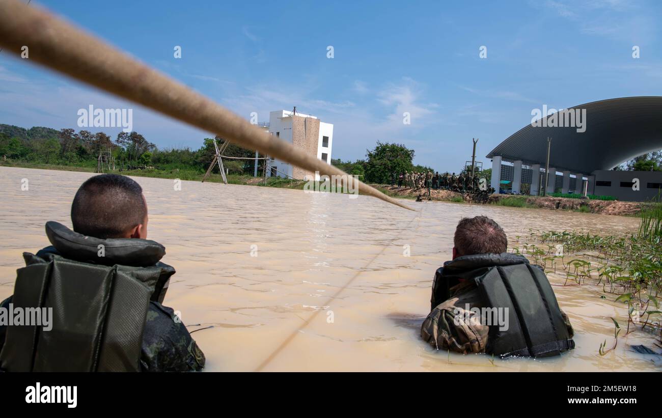A U.S. Army Soldier and a Royal Thai Army soldier wait in the shallows ...