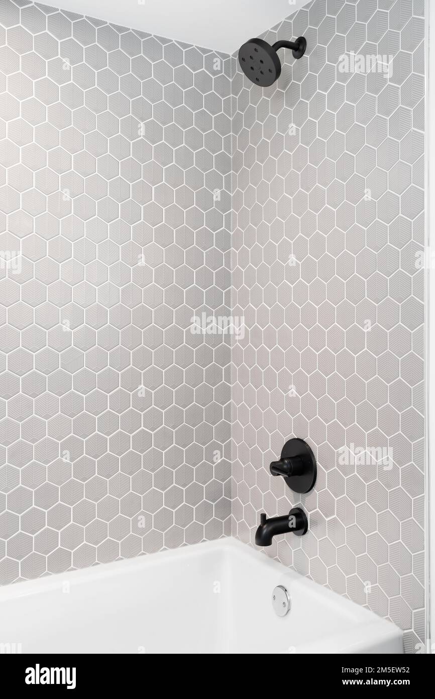 A shower detail with brown textured hexagon tiles, white bathtub, and ...