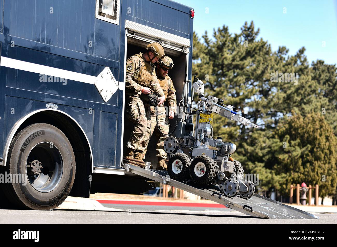 Two explosive ordnance disposal team members from the 8th Civil Engineer Squadron walk behind a ...