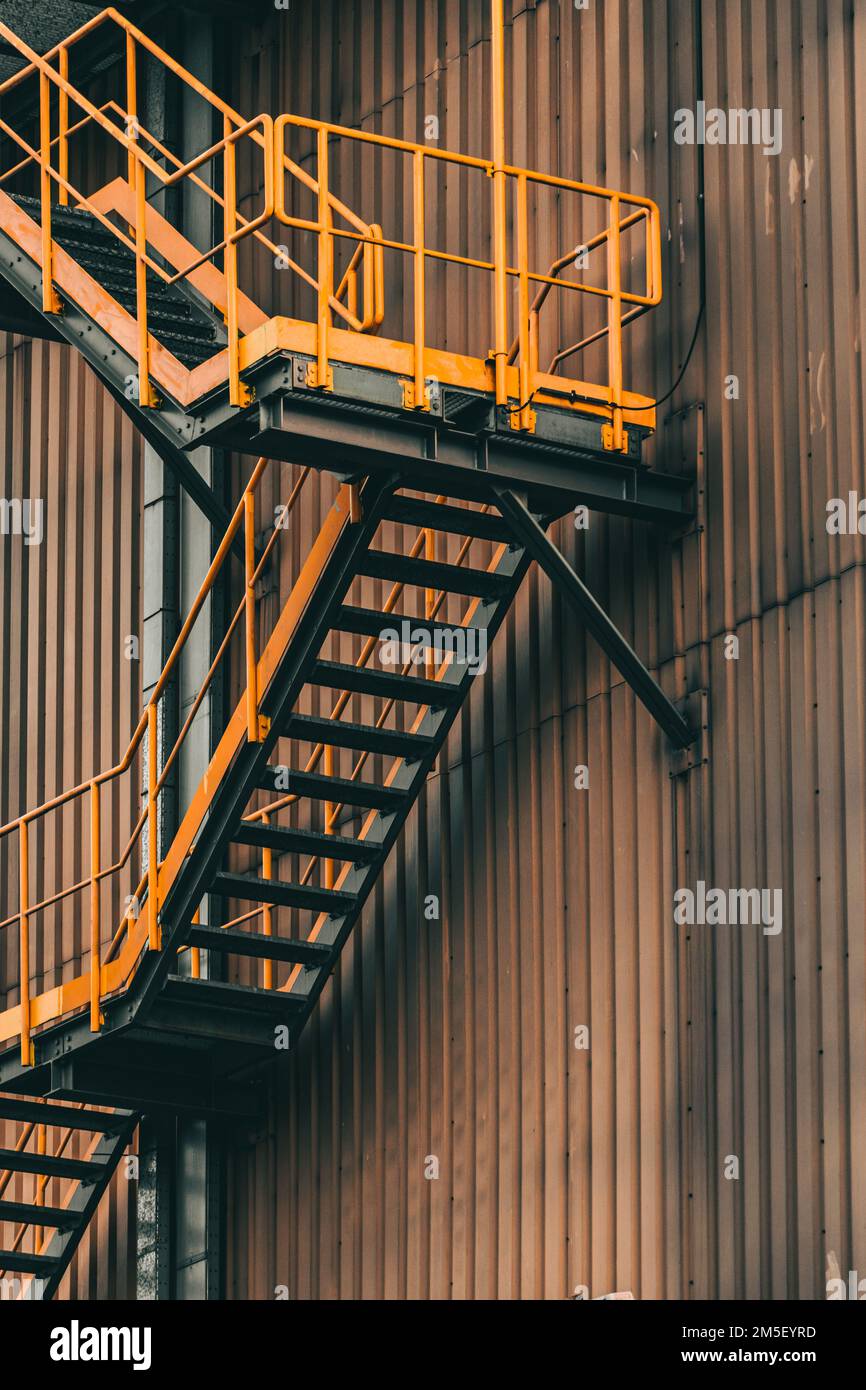 A vertical shot of the part of a structure with rusty orange wall and ...