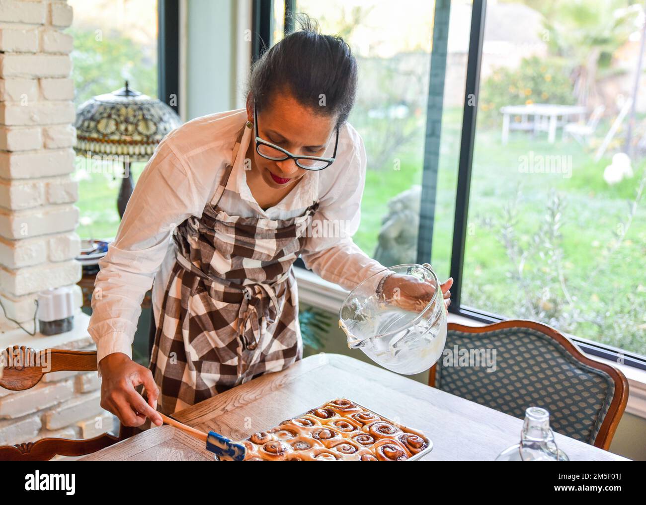woman laying out a large sheet of freshly baked cinnamon rolls neatly ...
