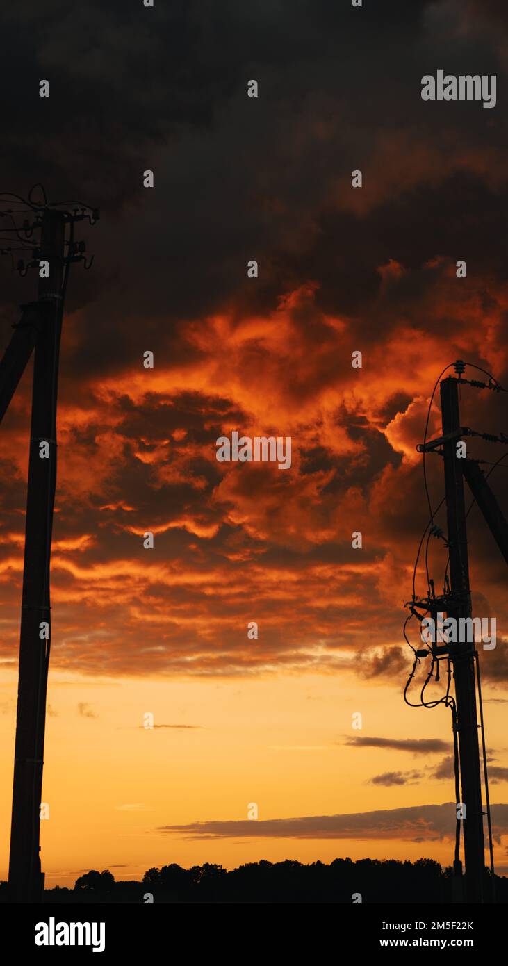 A vertical shot of utility pole silhouettes against the red sunset ...