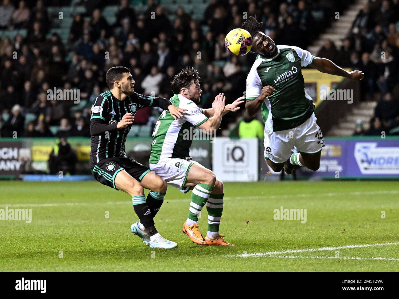 Hibernian's Rocky Bushiri (right) heads the ball clear from pressure ...