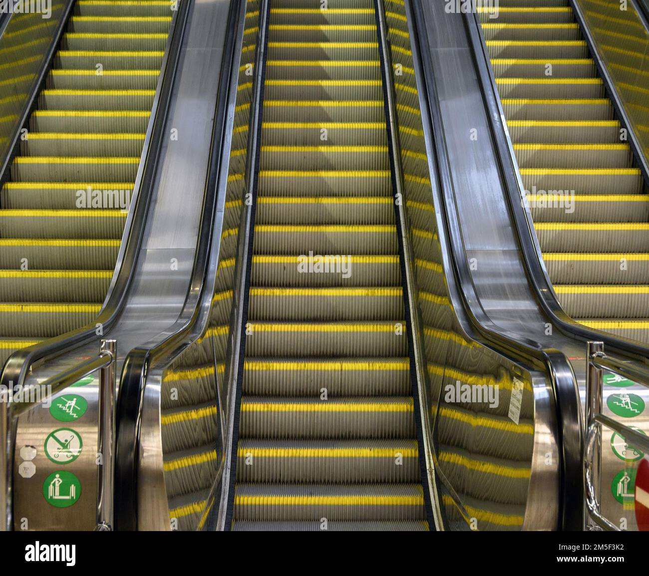 A low-angle of an escalator view with yellow stairs and three lines ...
