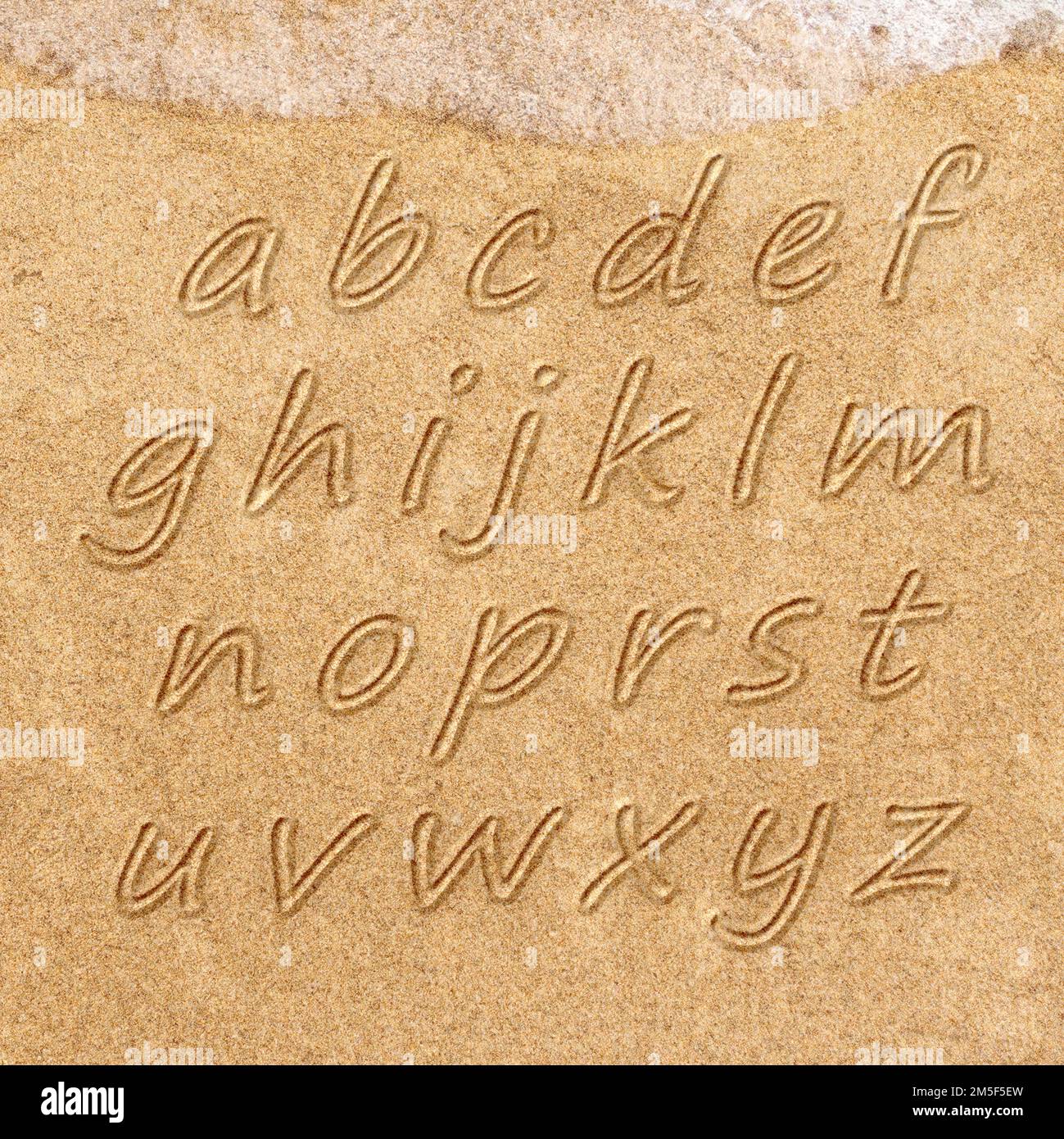 The alphabet written in sand on a beach Stock Photo - Alamy