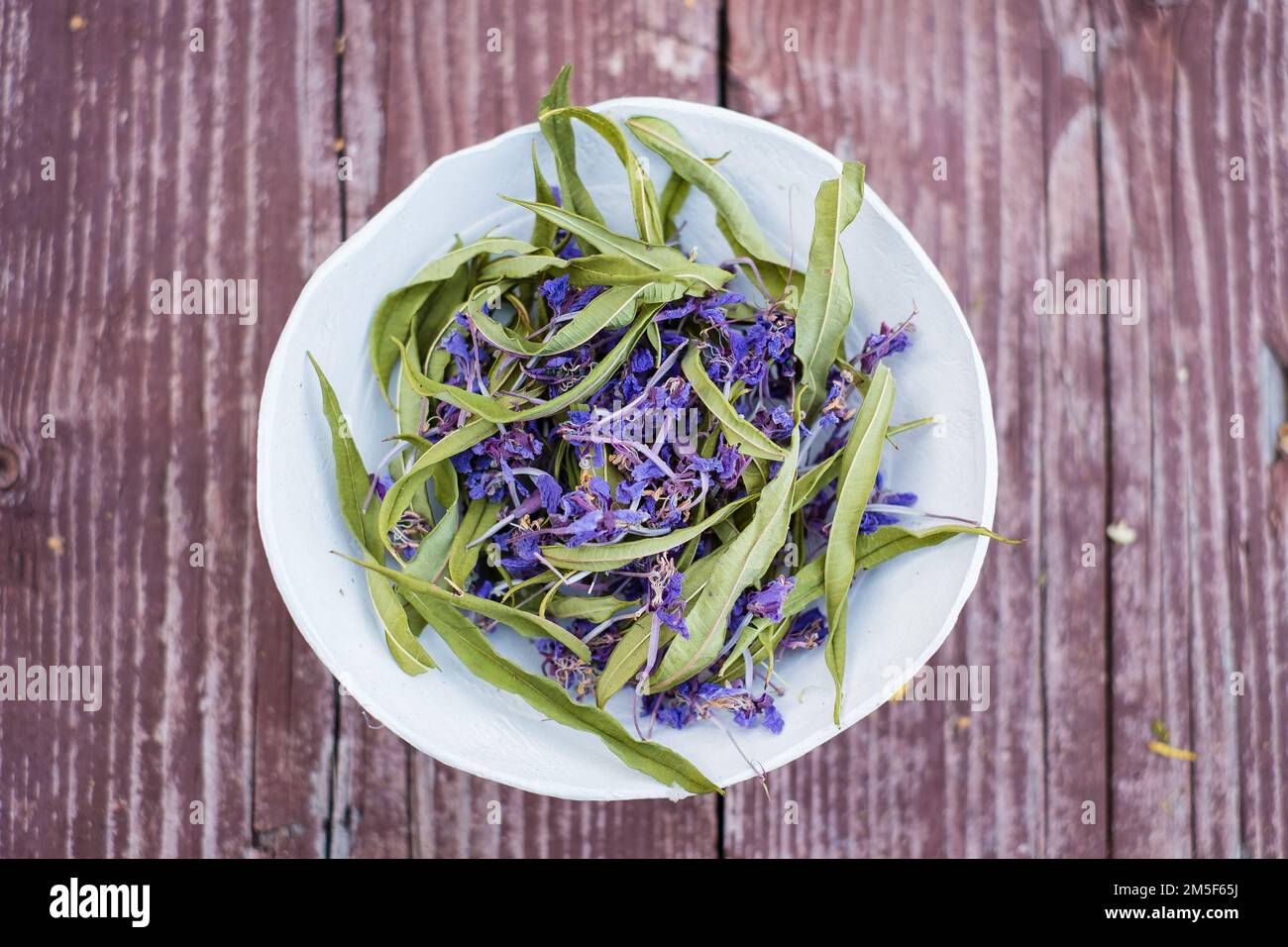 Dry herbal tea from fireweed flowers in a small clay bowl on wood ...