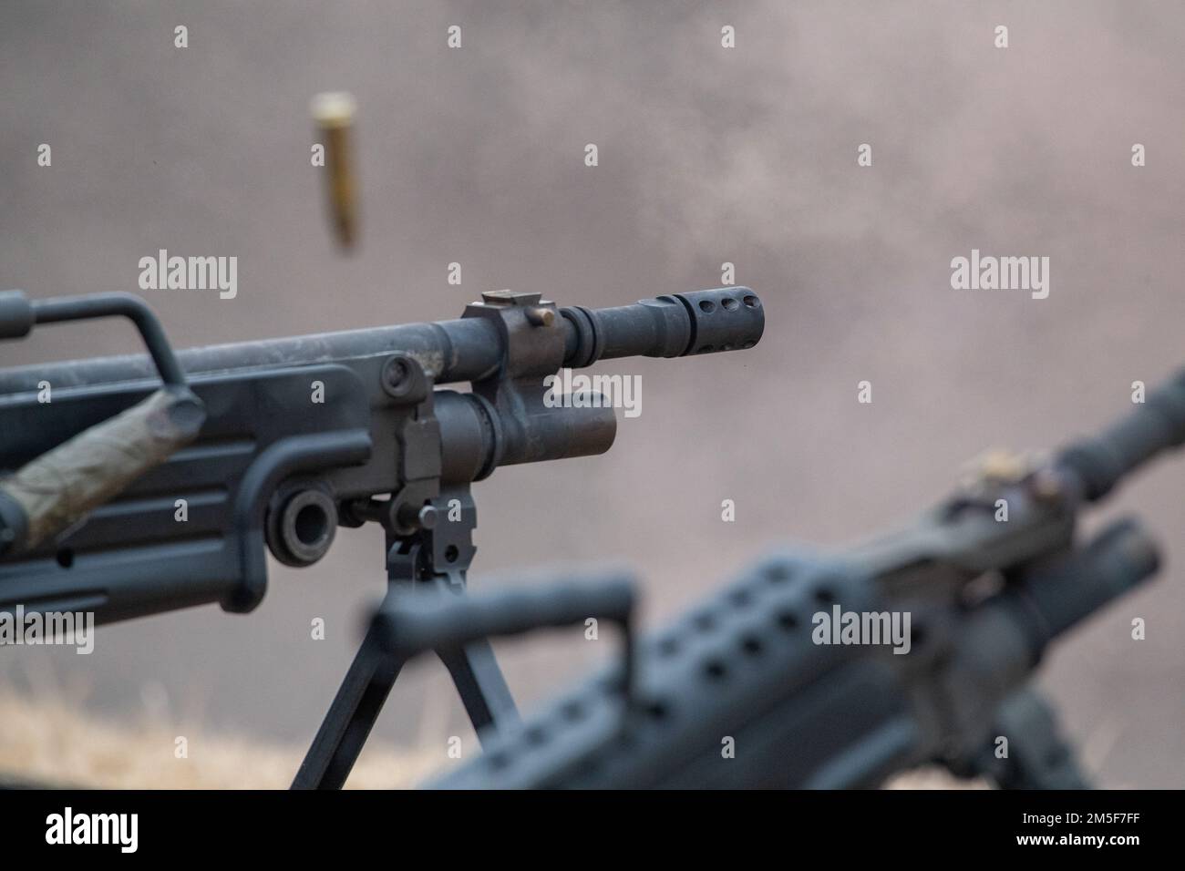 A shell casing launches out of an M249 machine gun as rounds are fired ...