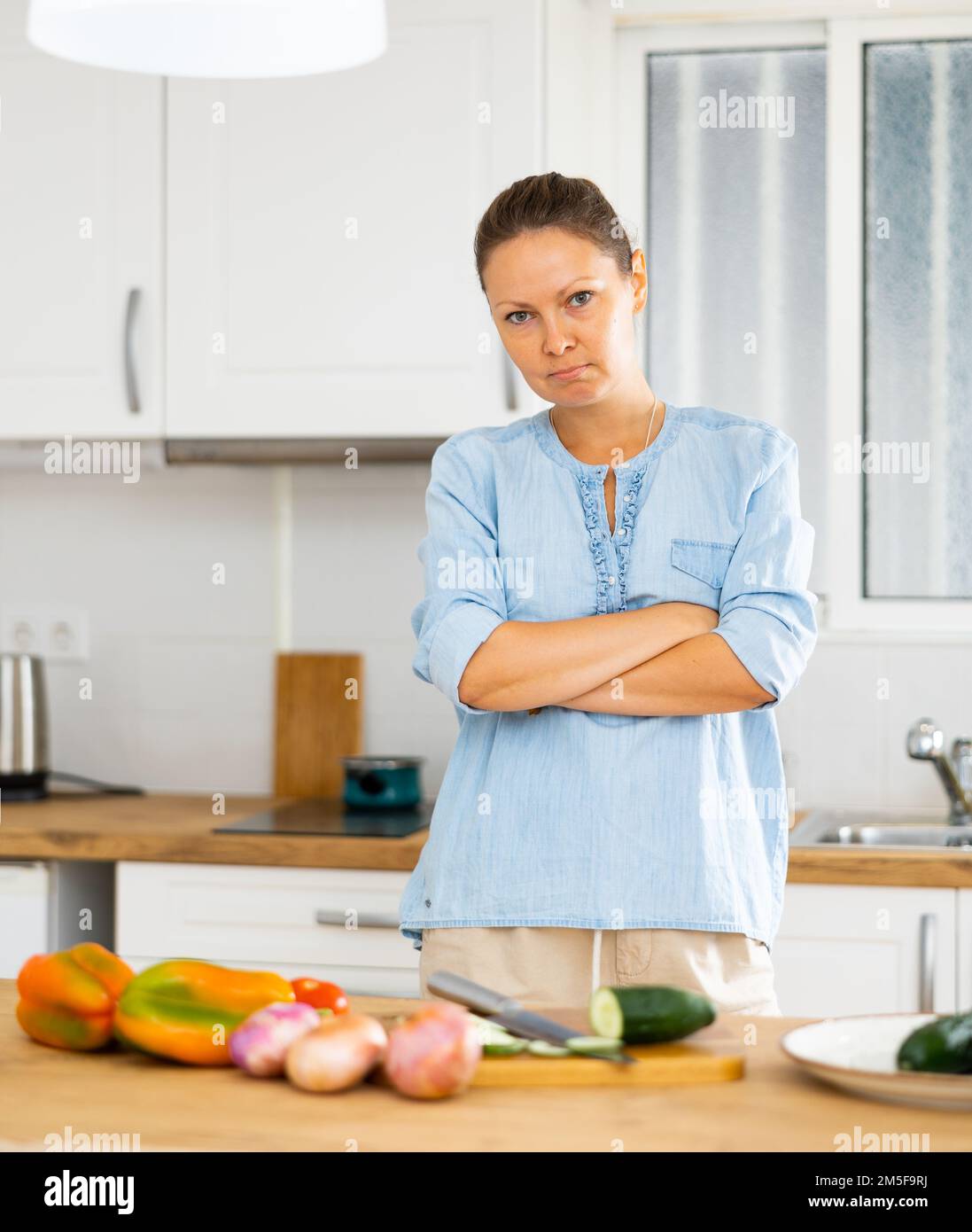 Sad young adult woman standing in kitchen Stock Photo - Alamy
