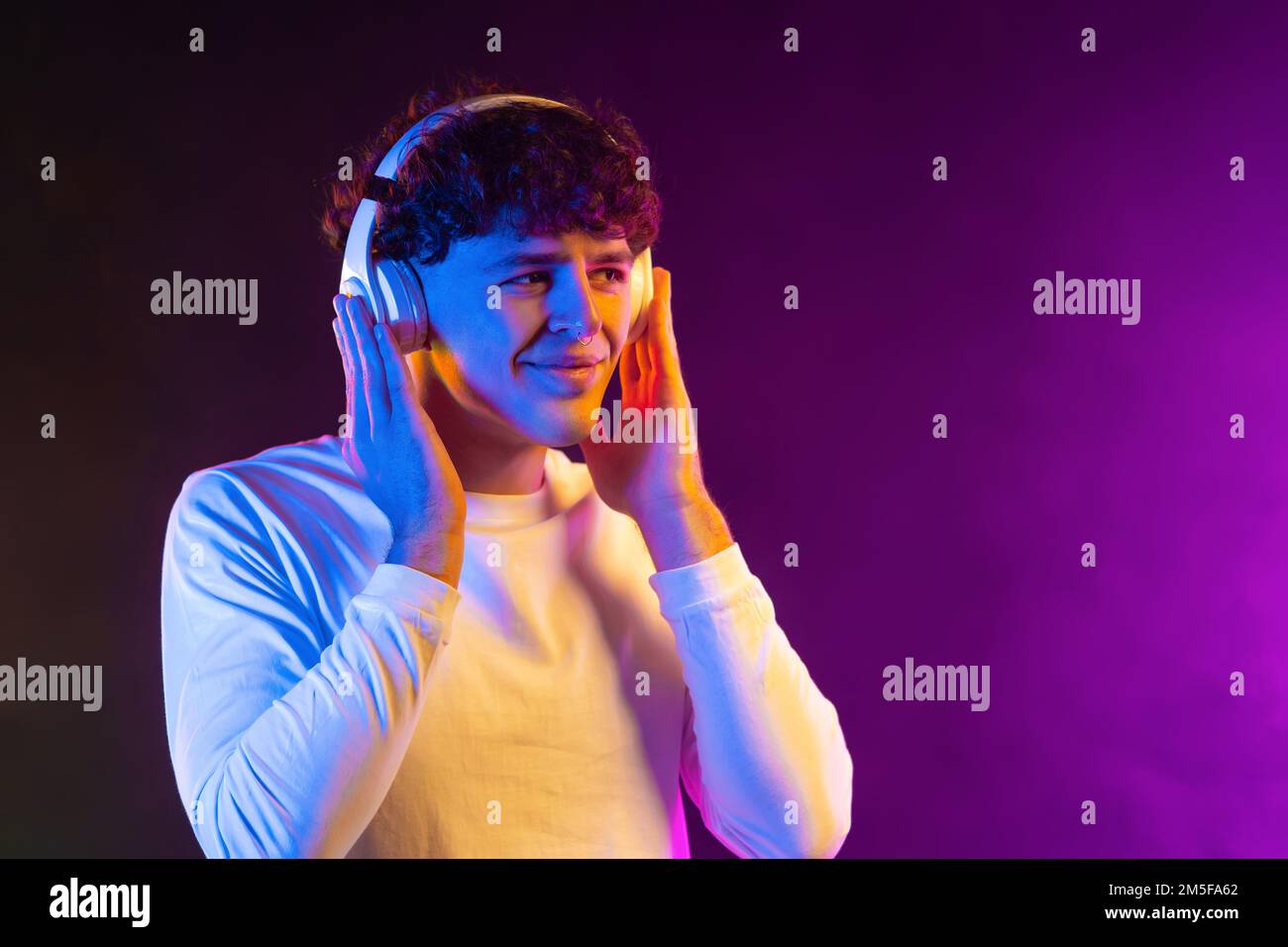 Handsome man listening music with headphones on gradient neon ...