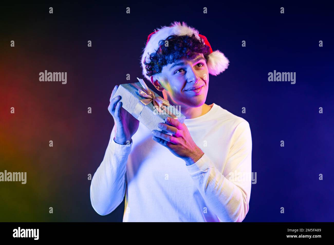 Excited man in Santa hat hold gift box with bow. He is happy and ...