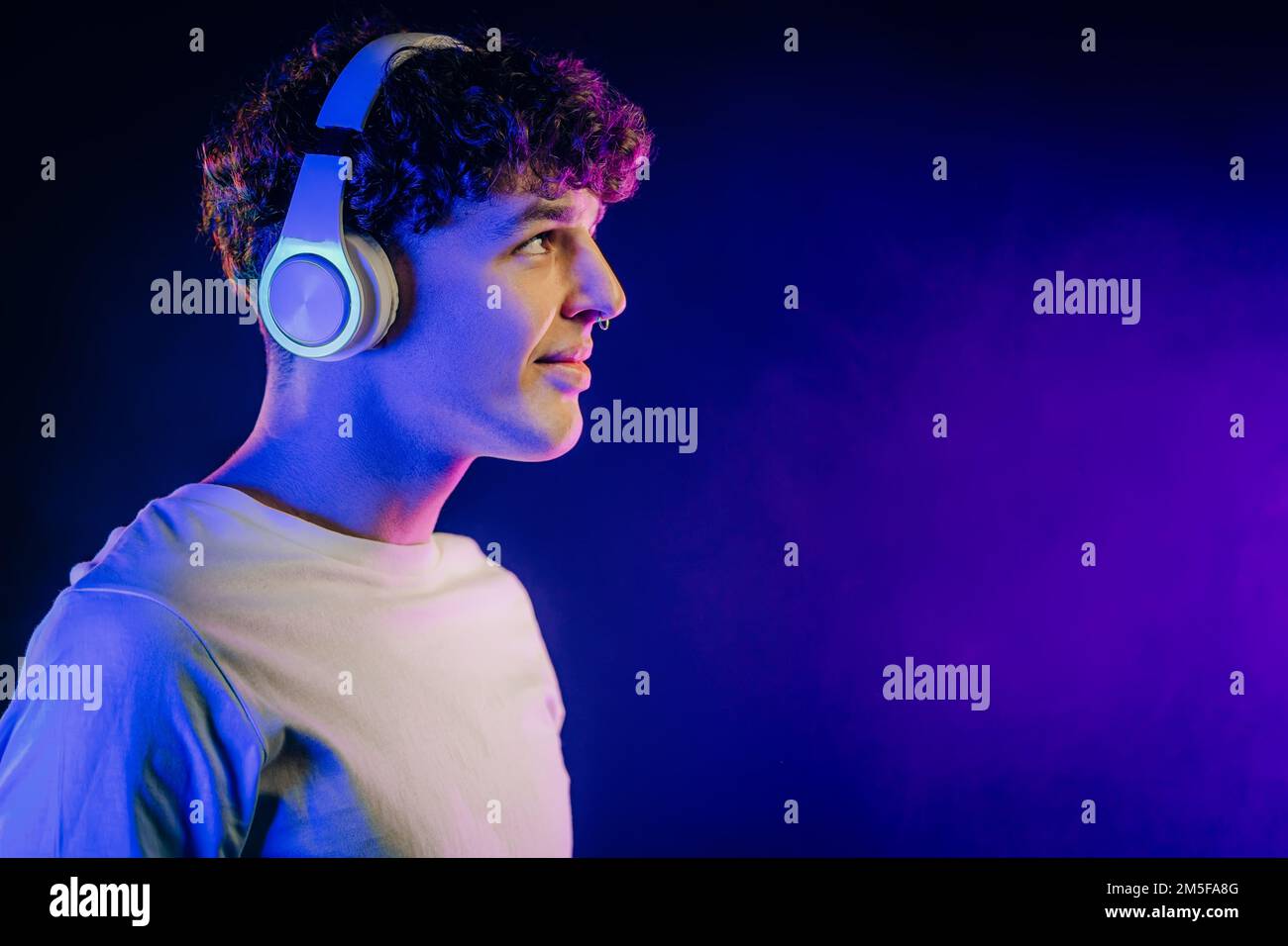 Handsome man listening music with headphones on gradient neon ...