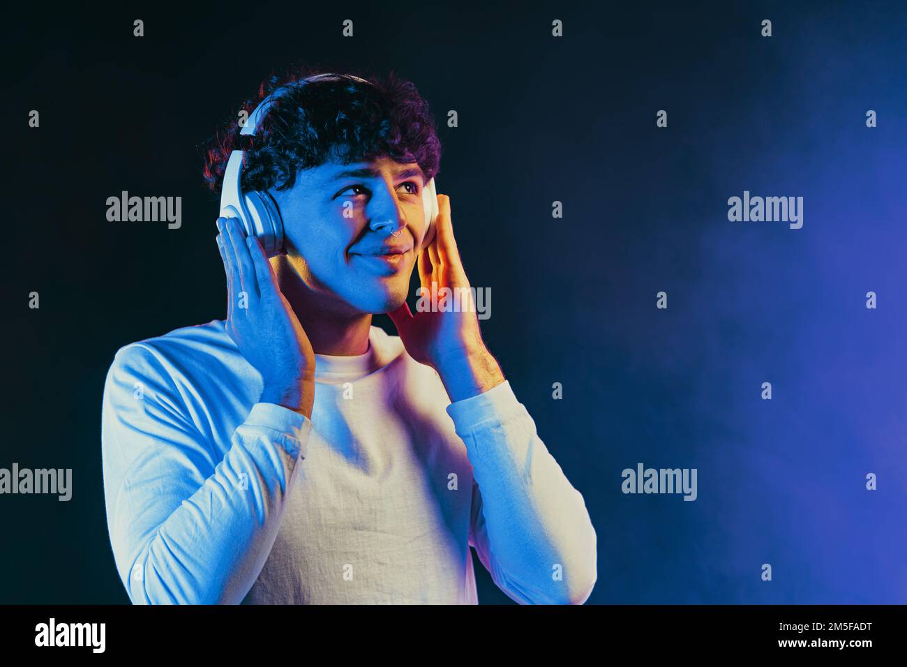Handsome man listening music with headphones on gradient neon ...