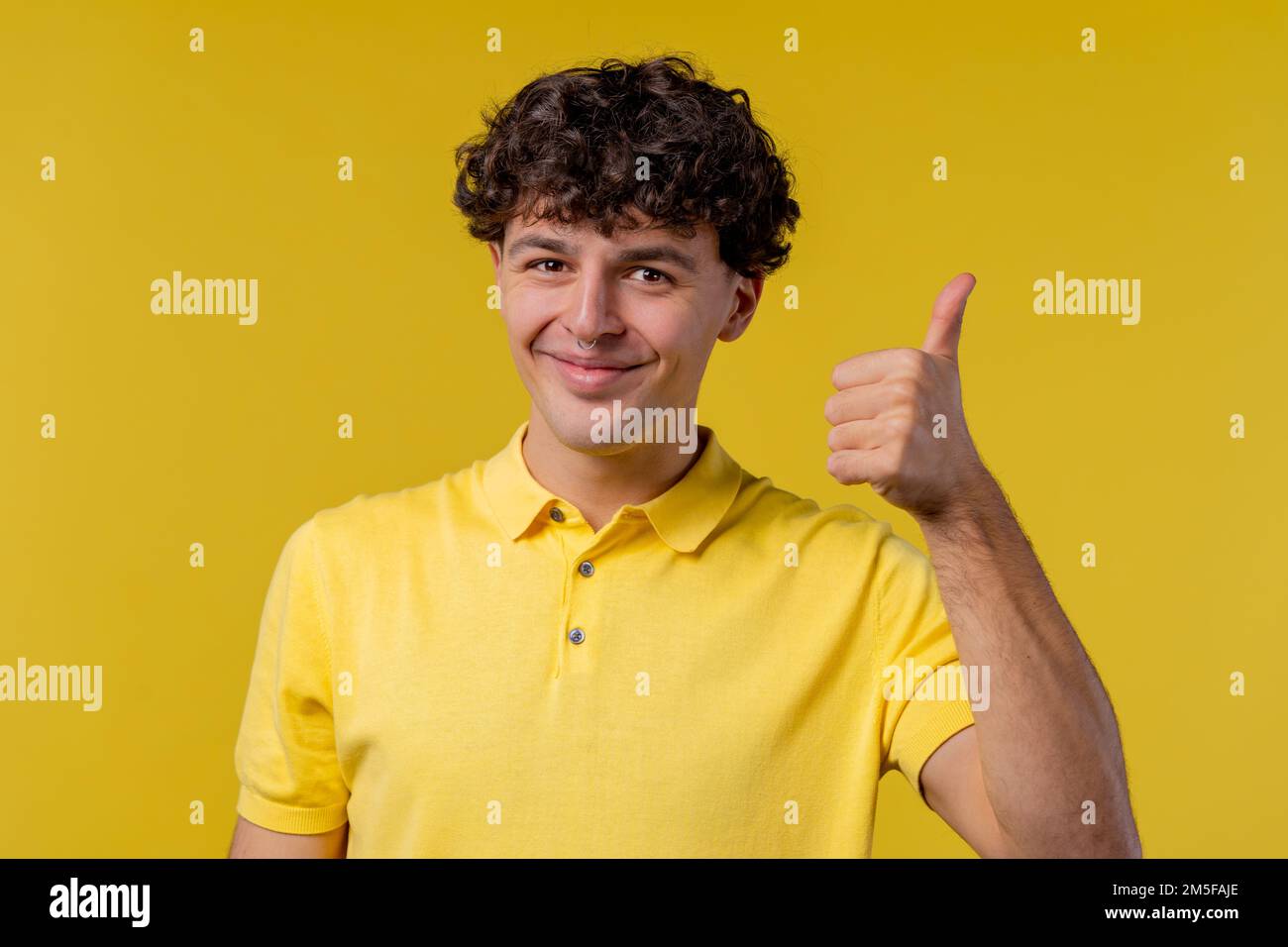 Positive curly man makes hand sign like, thumbs up gesture. Happy ...
