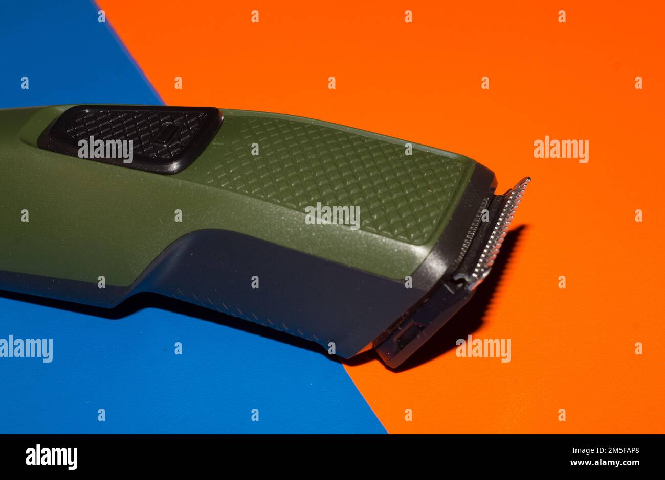 A closeup shot of a hair trimmer isolated on the blue and orange ...