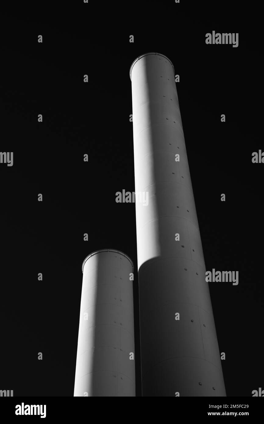 A grayscale vertical shot of two long pipes against black background ...