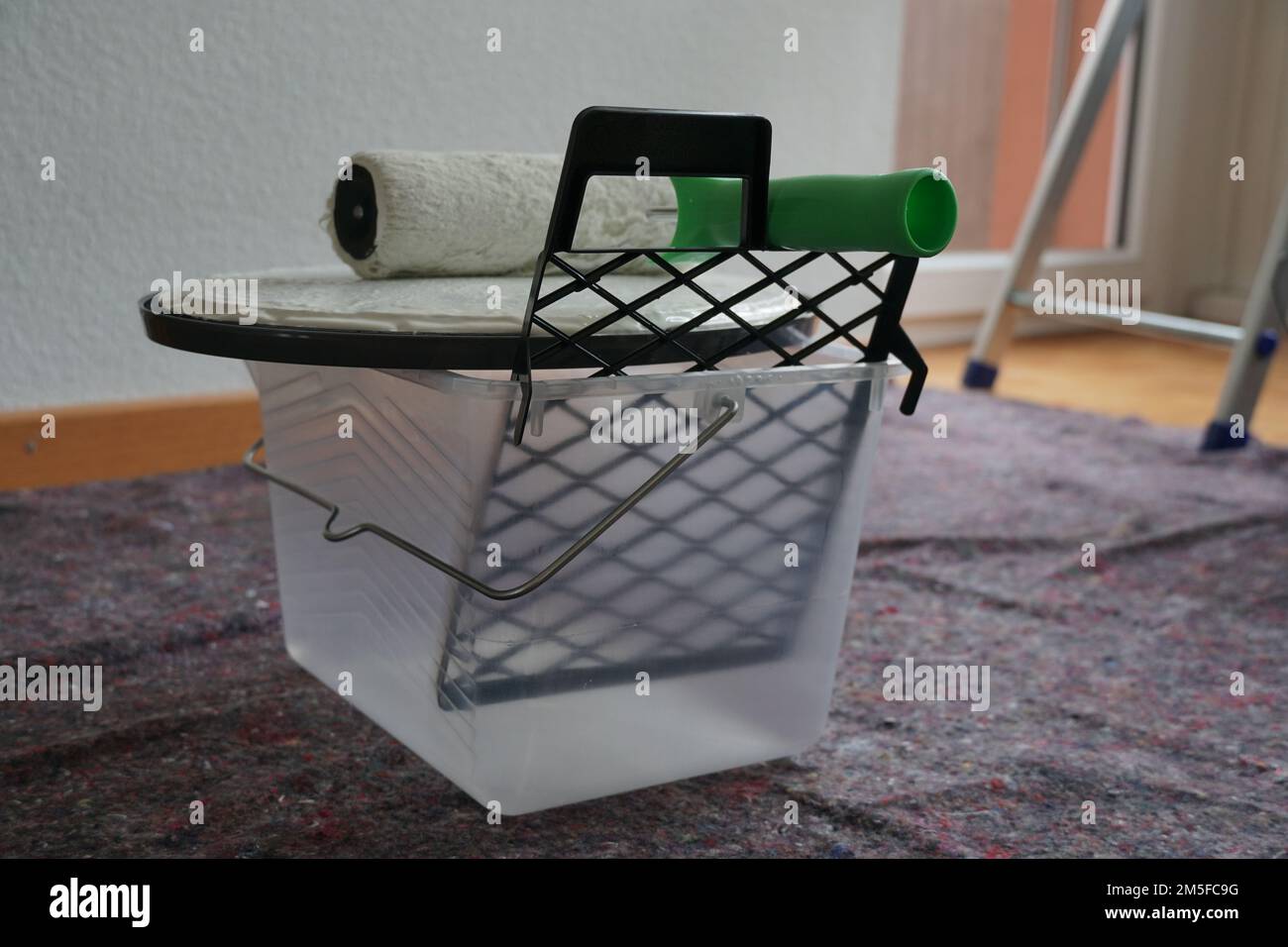 Room painting equipment on the floor. There is a paint roller, a ...