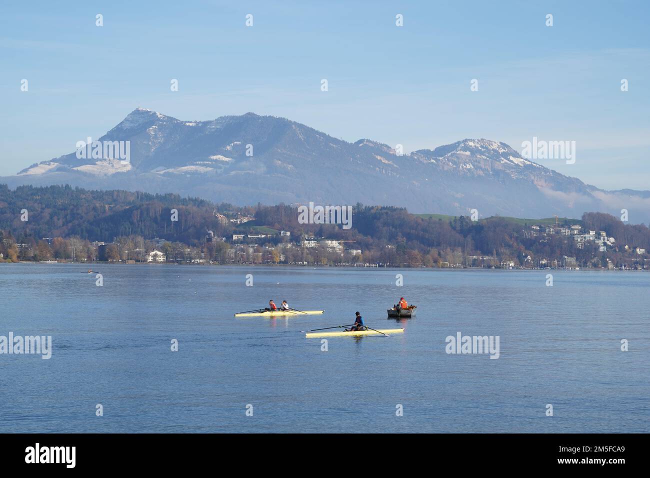 Two and one persons rowing boats exercising in lake lucerne under ...