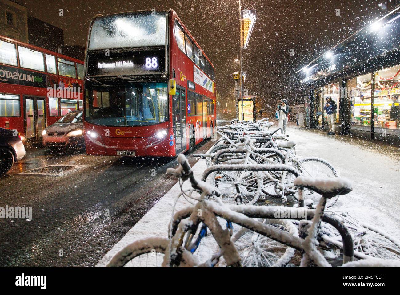 Snow falls on bicycles outside Stockwell Underground Tube Station as a ...