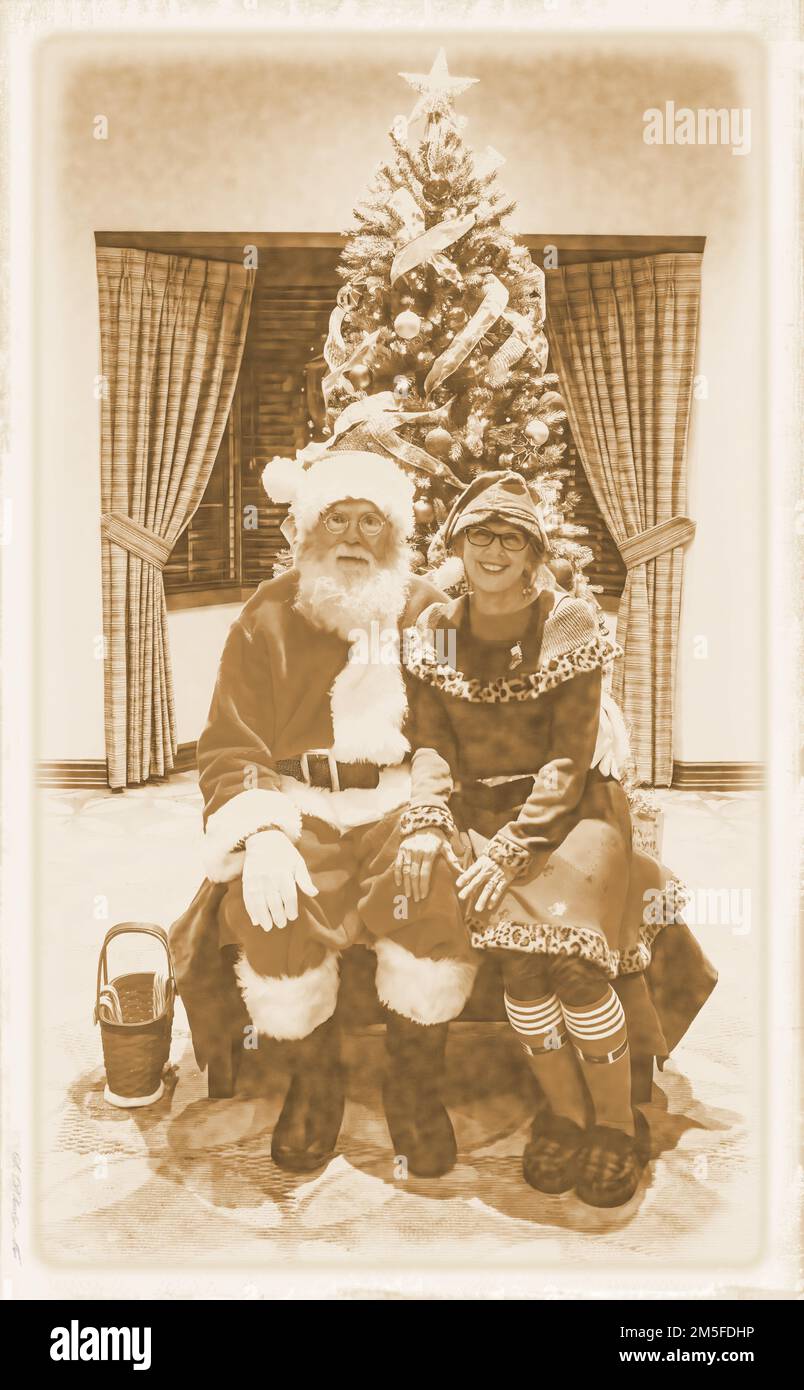 Santa Claus and his elf sitting in front of the Christmas tree ready to ...