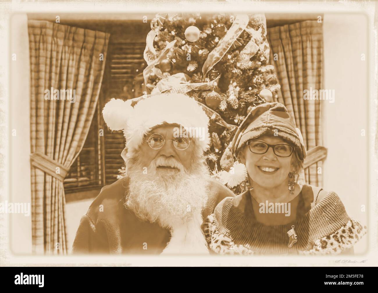 Santa Claus and his elf sitting in front of the Christmas tree ready to ...