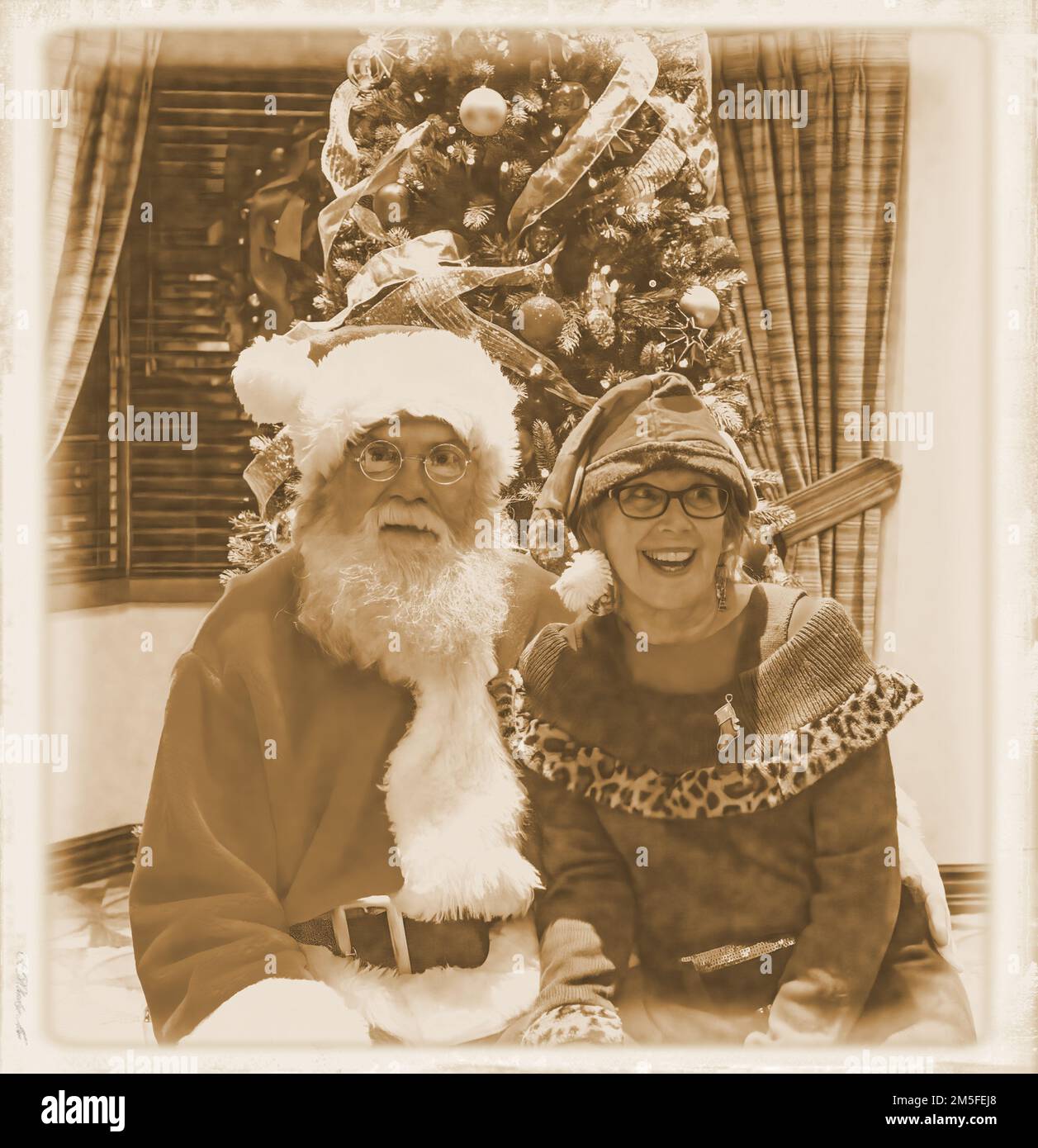Santa Claus and his elf sitting in front of the Christmas tree ready to ...