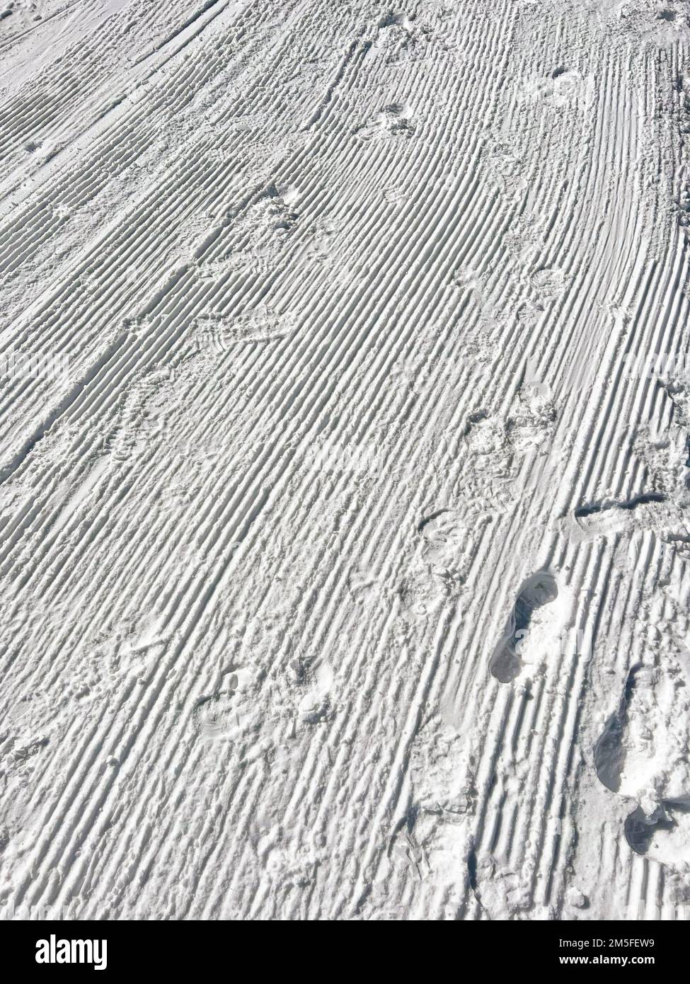A vertical closeup of sunlit snow flows with footsteps on Stock Photo ...
