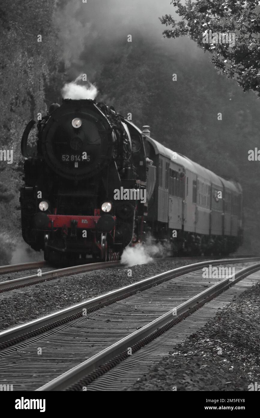 A selective color of steam train with railways with misty background ...