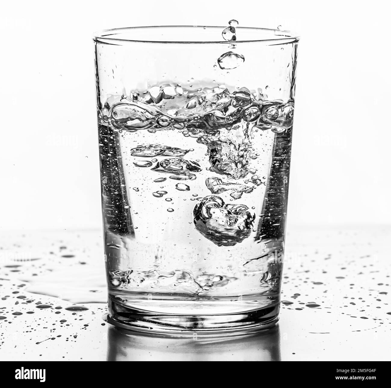 A closeup of a glass of water with bubbles isolated on a reflective ...