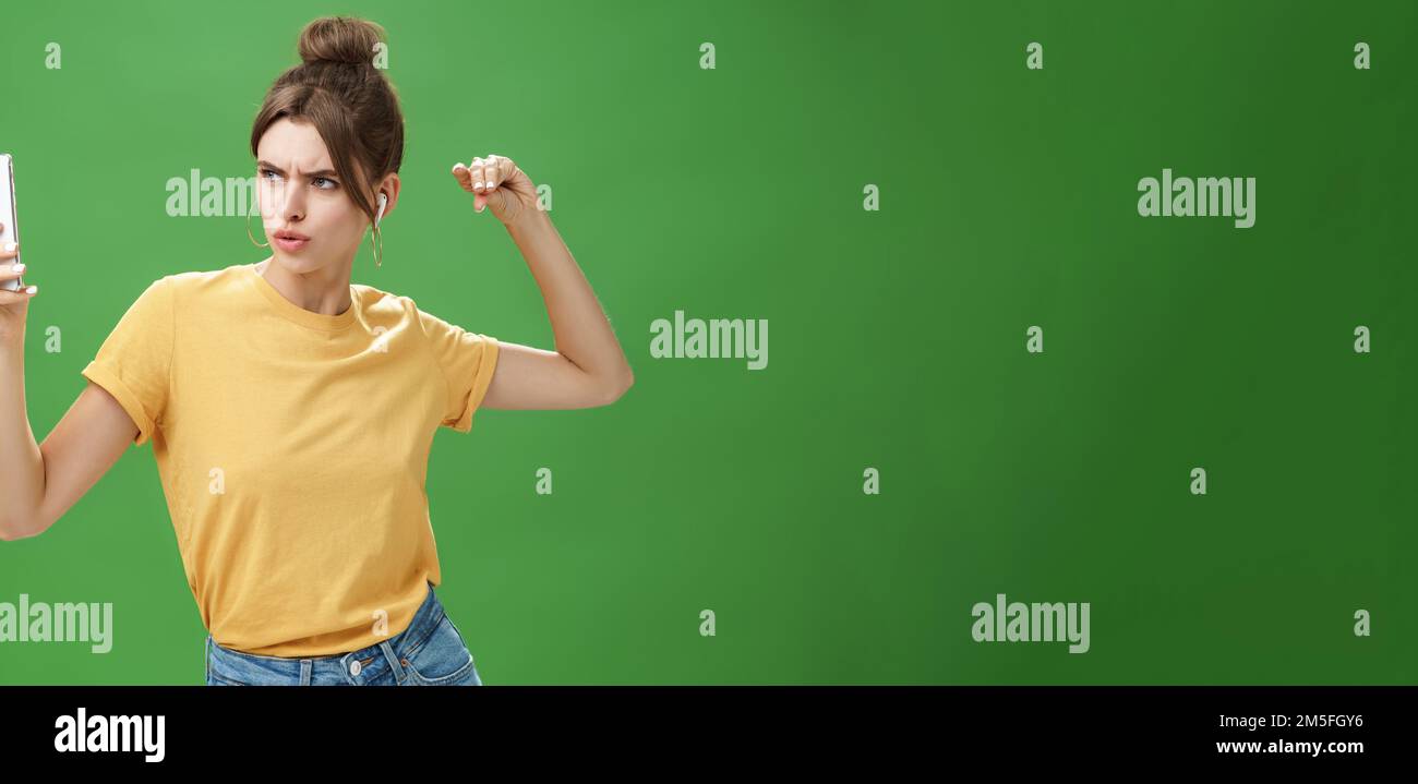 Woman making serious look to take selfie while listening music in ...