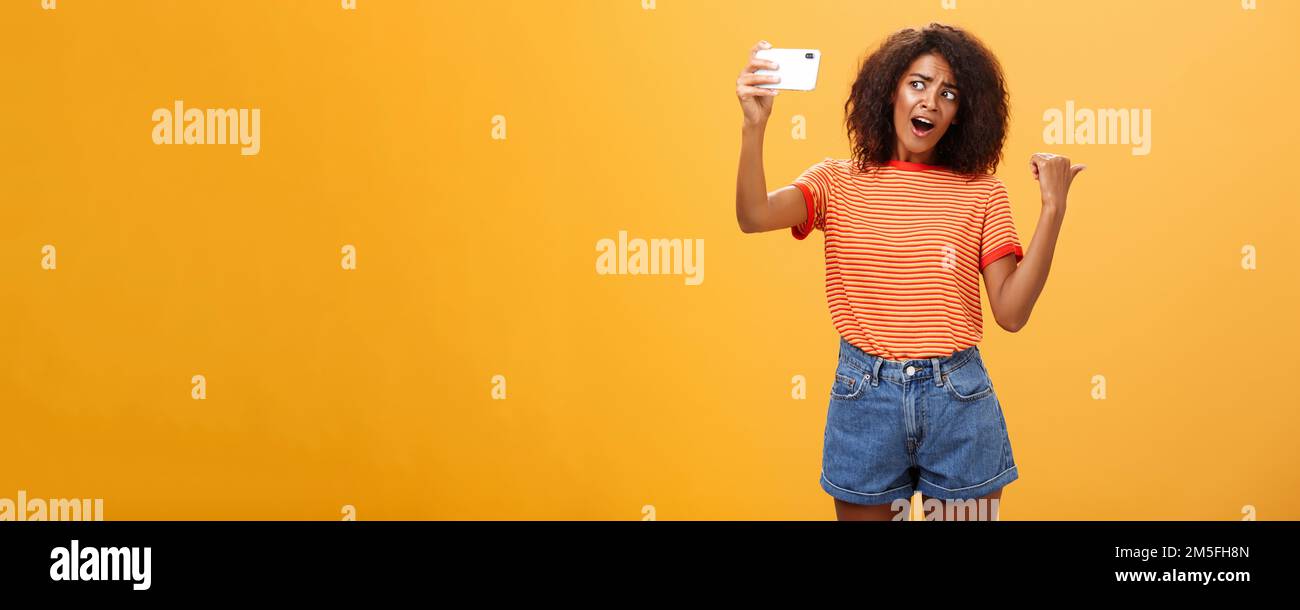 Woman recording video blog pointing at strange object behind her ...
