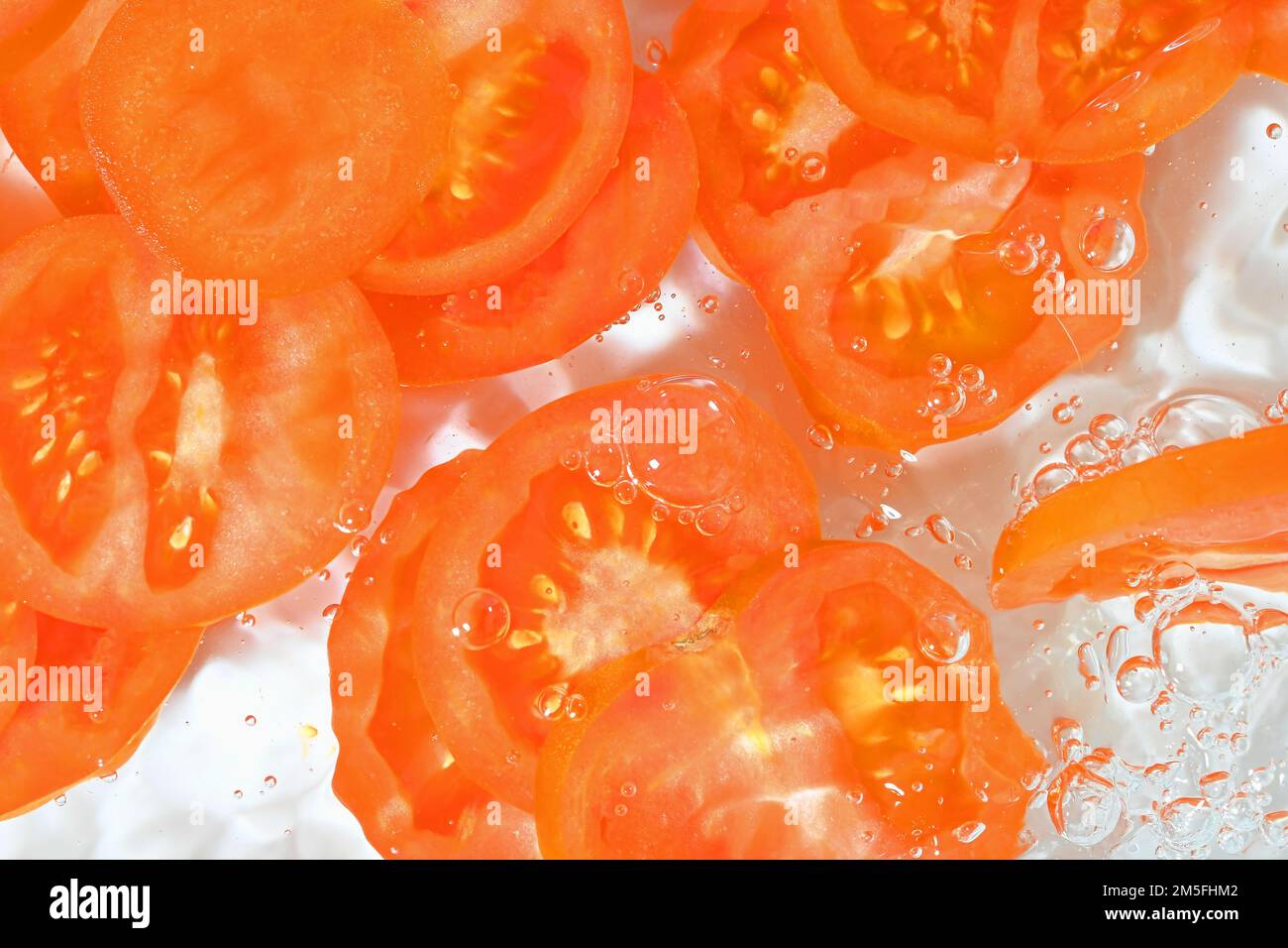 Tomato close-up in liquid with bubbles. Slices of red ripe tomato in ...