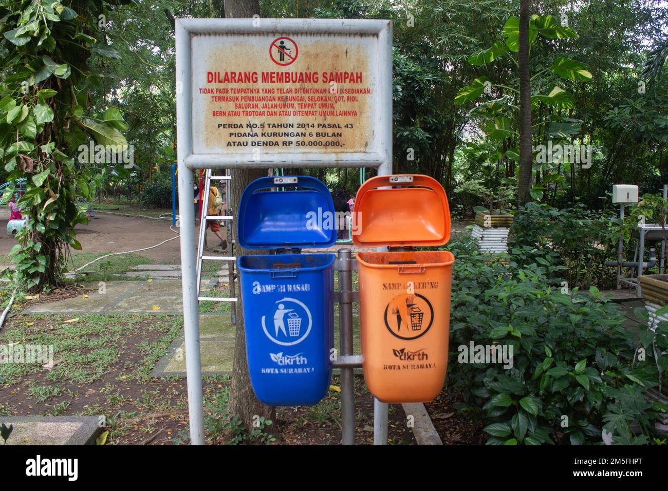 A prohibited littering sign. Blue and orange trash bin in public park ...