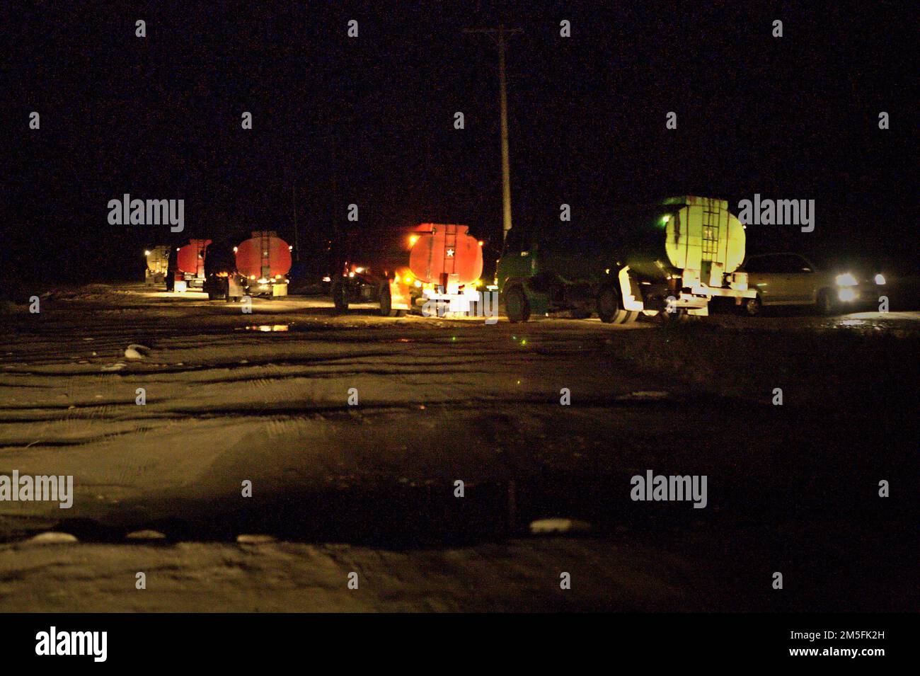 A convoy of trucks transporting fuel are seen moving at night on a road ...