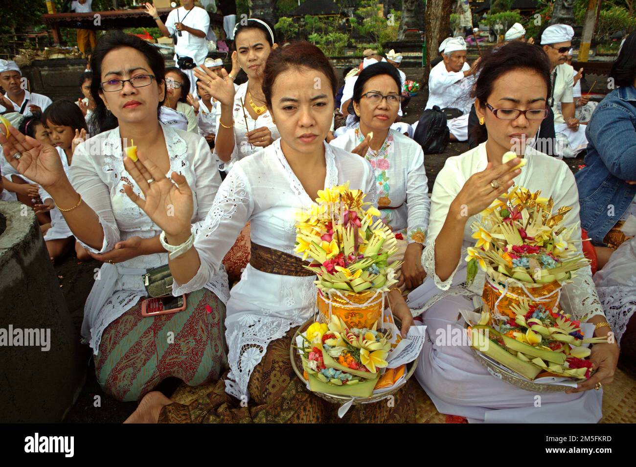 A Balinese clan conducting a ritual to honor and purify the spirits of ...