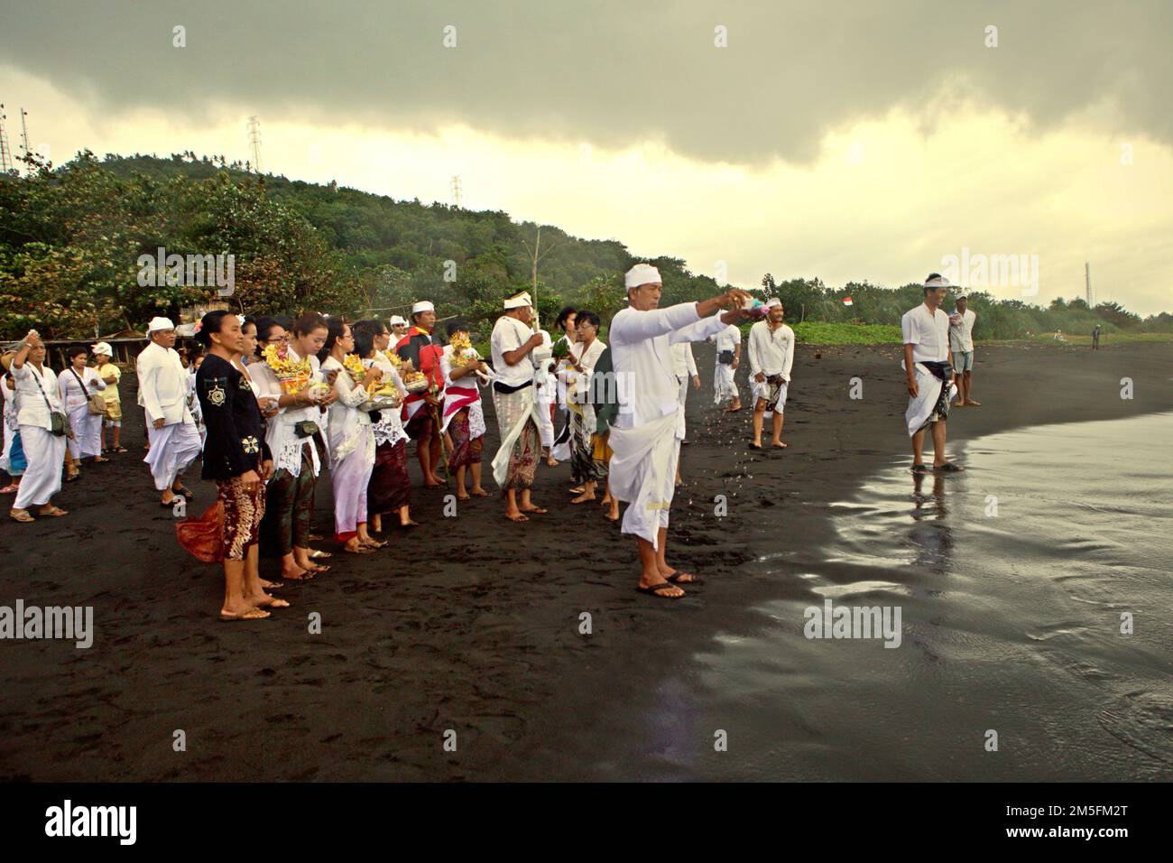 A Balinese clan conducting a ritual to honor and purify the spirits of ...
