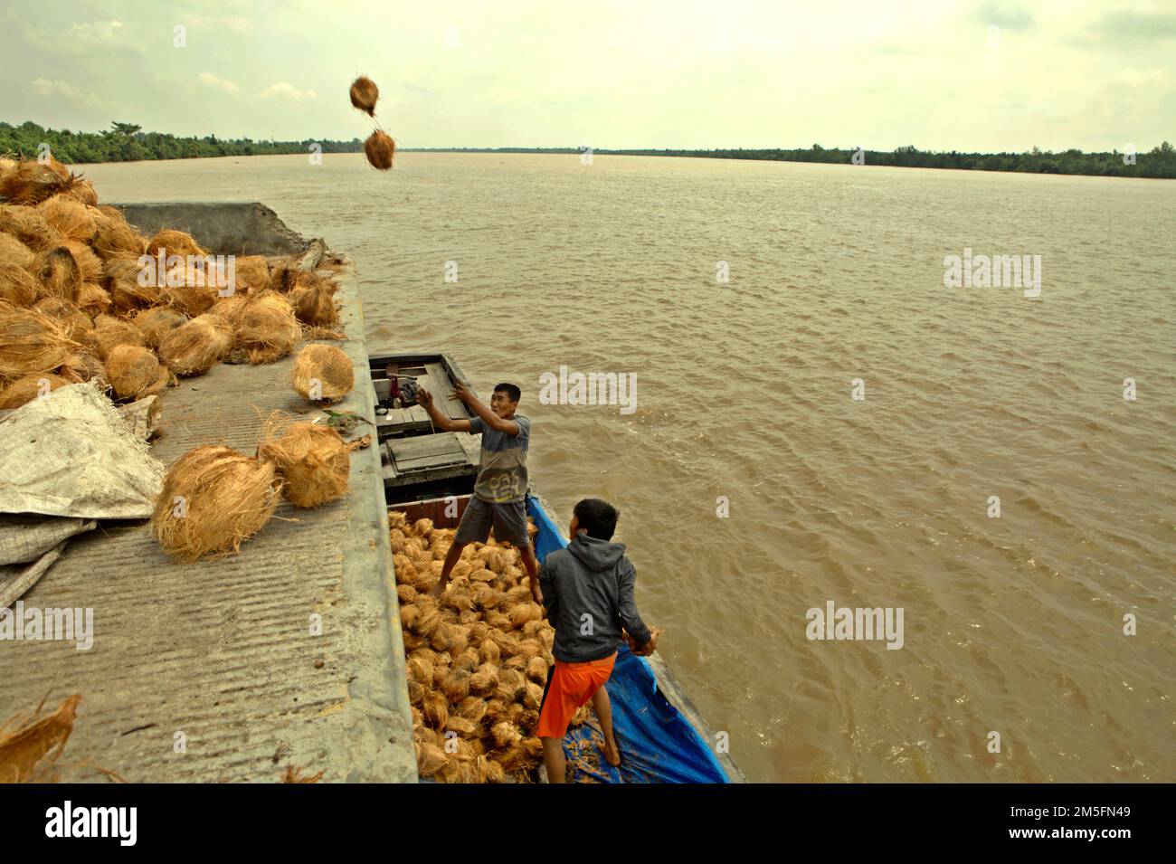 Men are standing on a boat tied to the platform of a riverport on ...