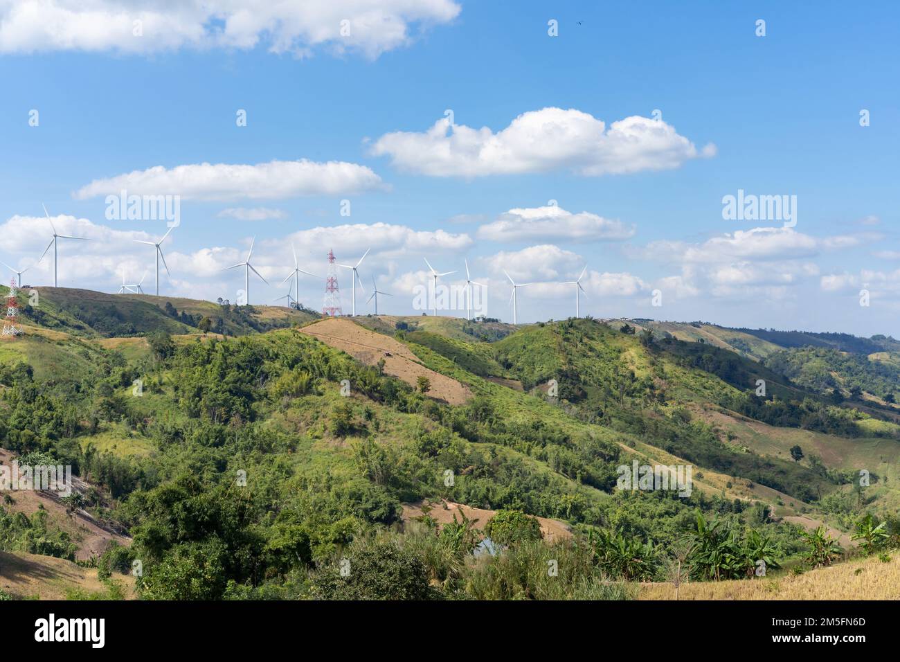 The wind turbines in the top of the grass hill underneath the group of ...