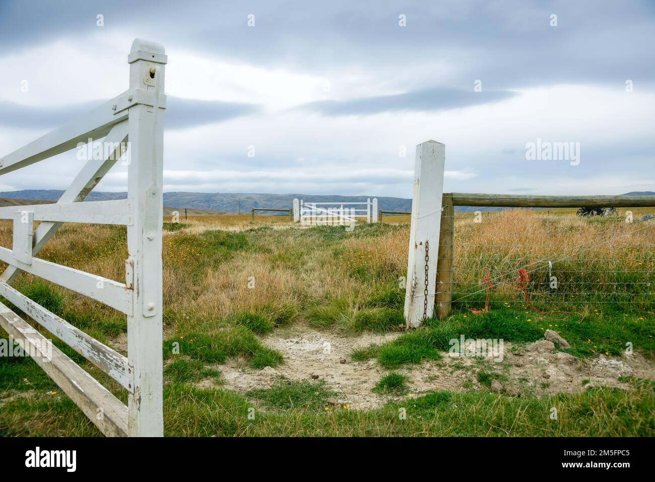 Open gate to field and distant hills leading to another gate in ...