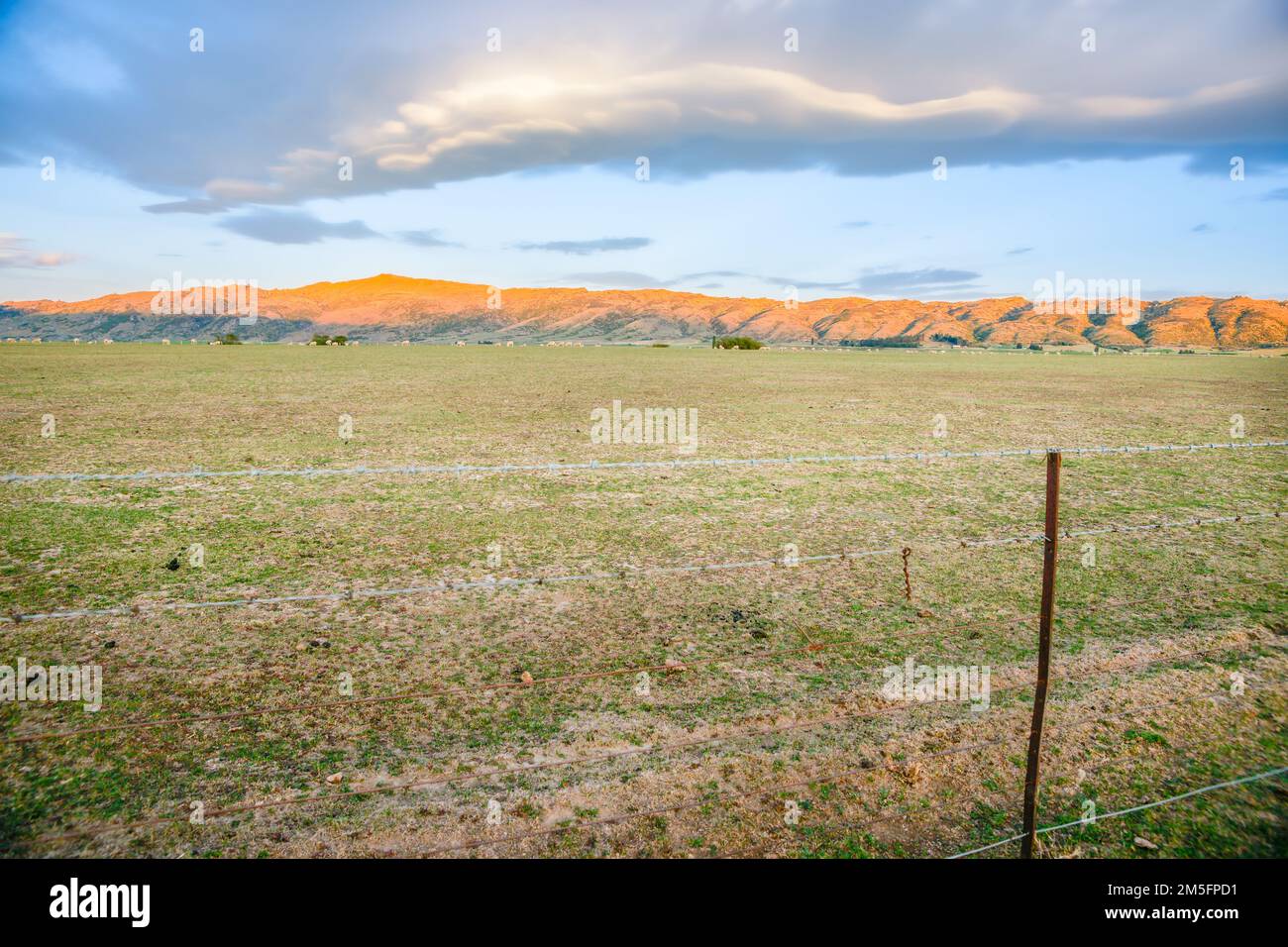Sunset turns distant mountains golden beyond wide flat landscape Stock ...