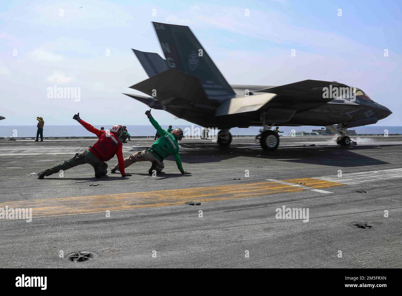 PHILIPPINE SEA (March 15, 2022) Sailors signal an F-35C Lightning II, assigned to the "Black ...