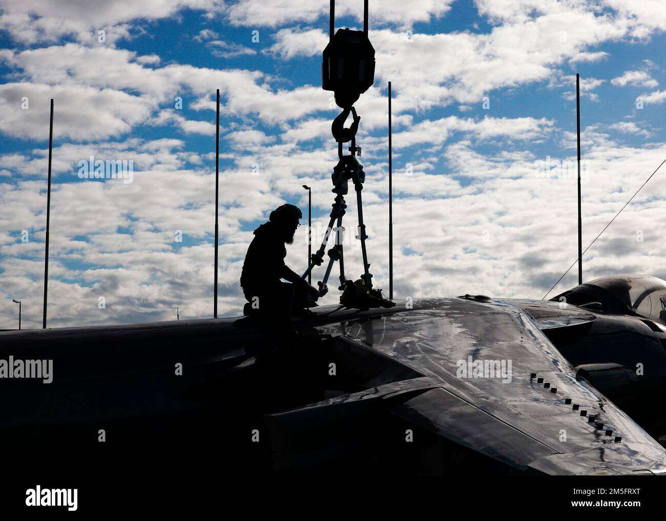 A Fleet Readiness Center East employee fastens an AV-8B Harrier to a ...