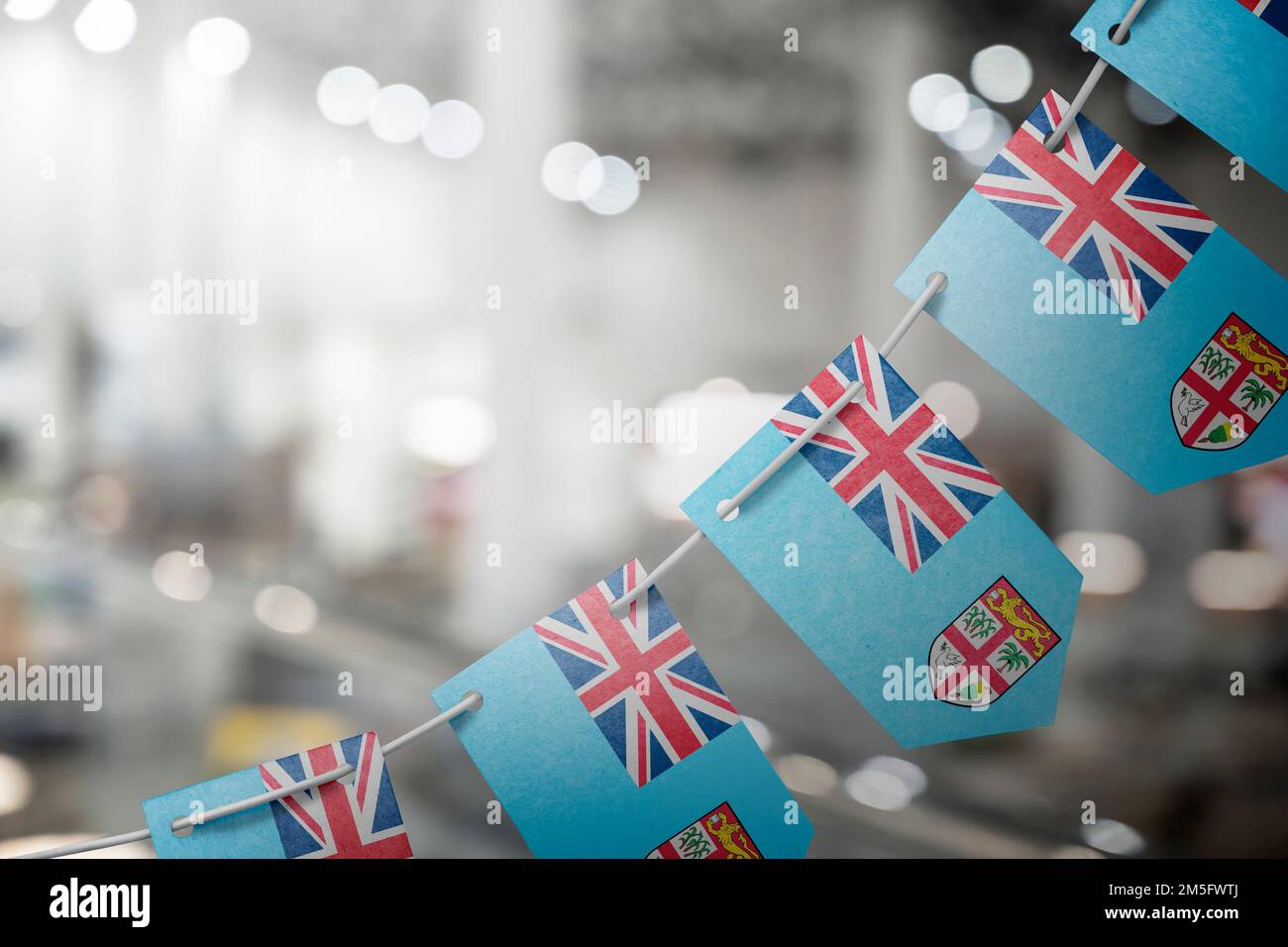 A garland of Fiji national flags on an abstract blurred background ...