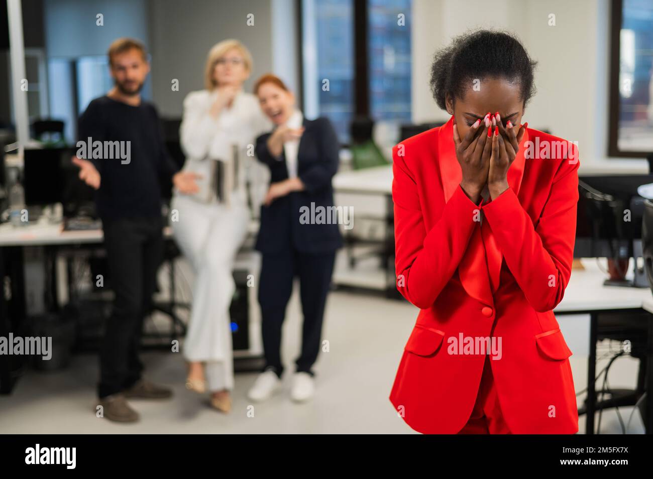 Young african woman crying because of the ridicule of colleagues ...
