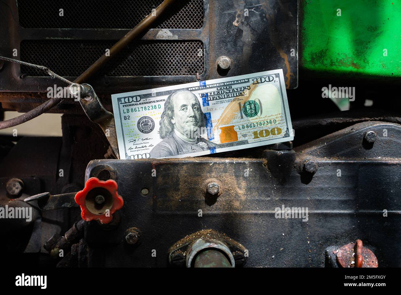 Hundred dollar bill on a tractor engine close-up. Money and the ...