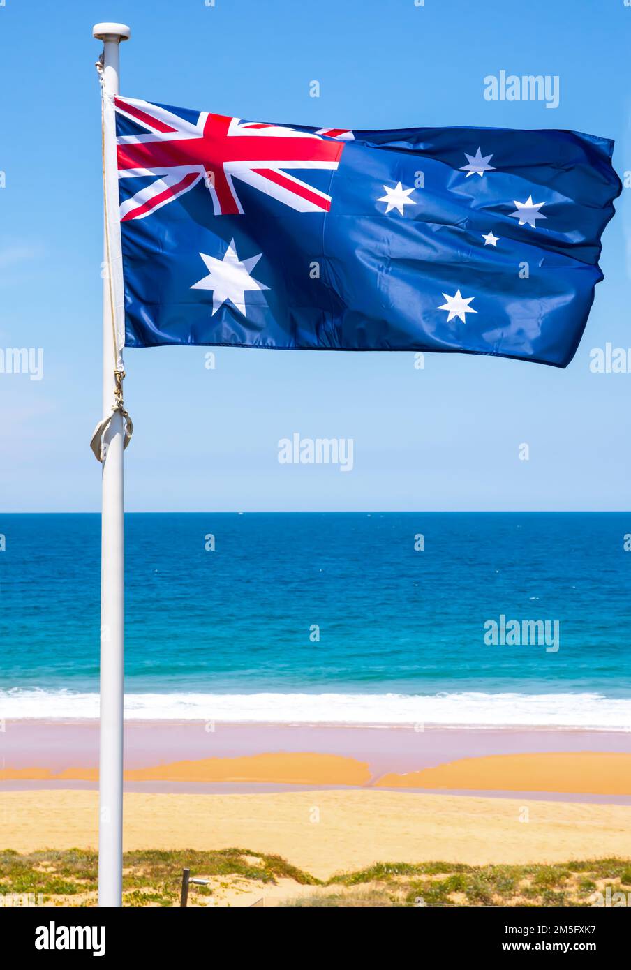 Australian flag flying against a blue sky,ocean and beach Stock Photo ...