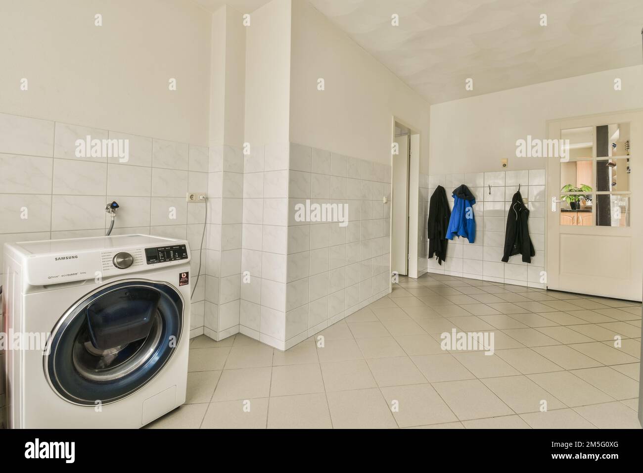 a laundry room with a washer, dryer and clothes hanging on the wall ...