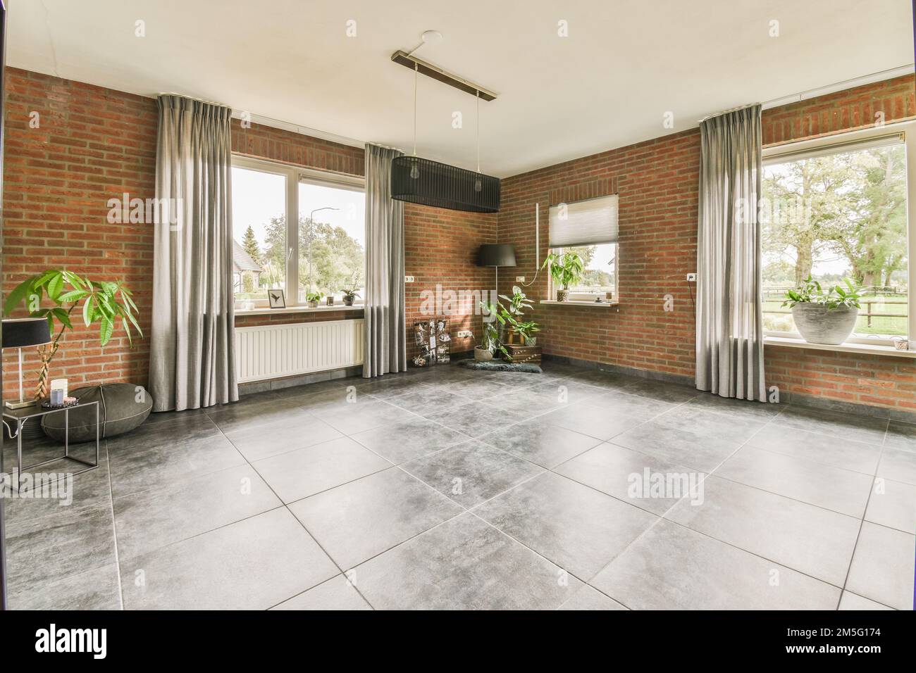 a living room with red brick walls and grey tiles on the floor, there ...