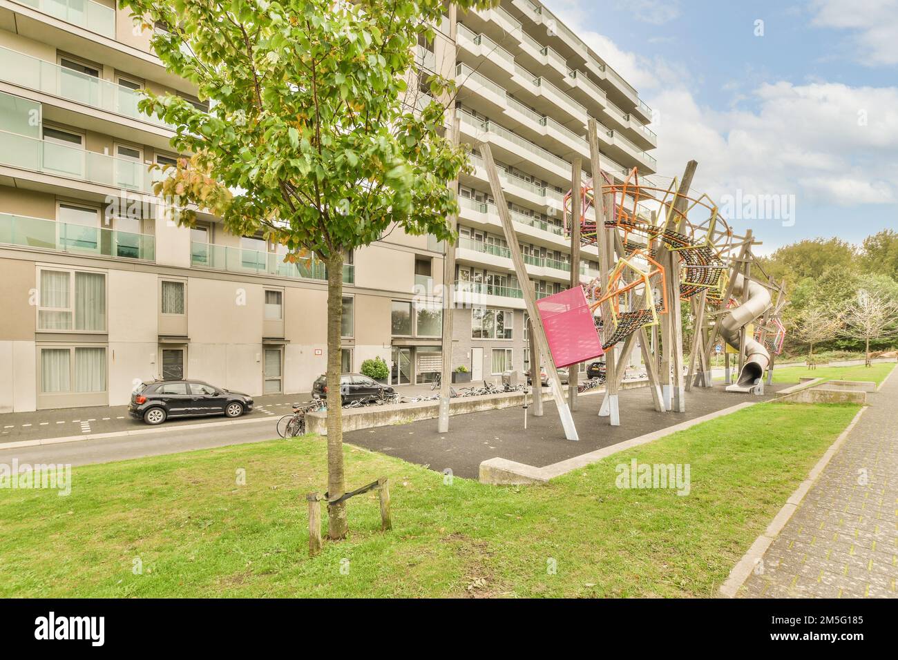 an apartment building with a playground in the front and cars parked on ...