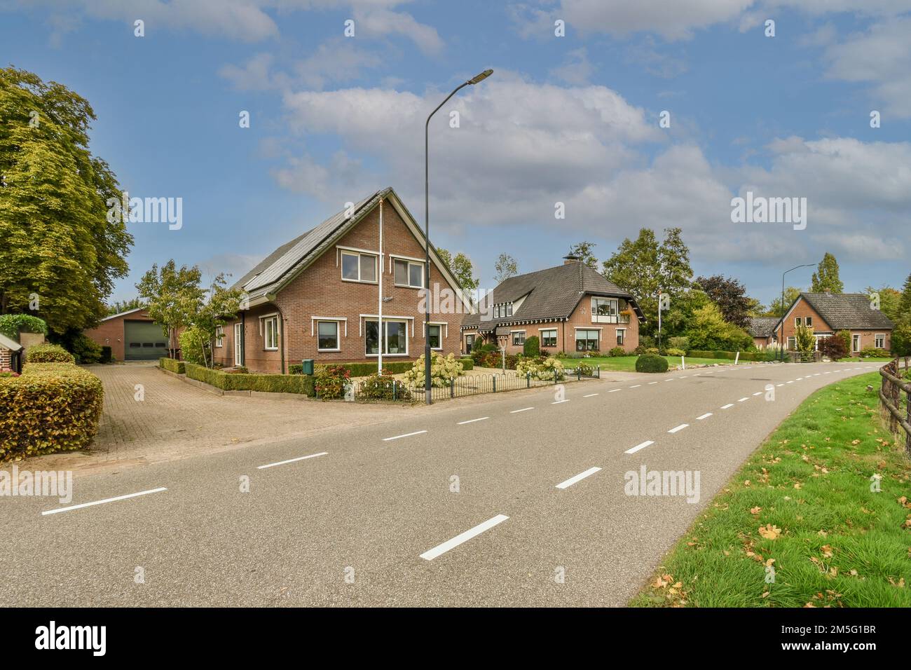 a street with houses in the background and trees on both sides, along ...