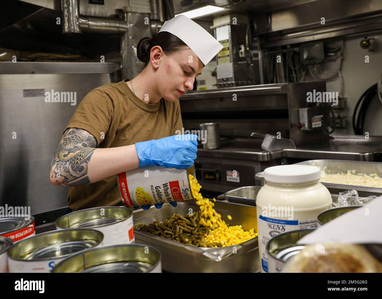 ATLANTIC OCEAN (March 16, 2022) – Culinary Specialist 3rd Class Alexandria Martinez adds a can ...